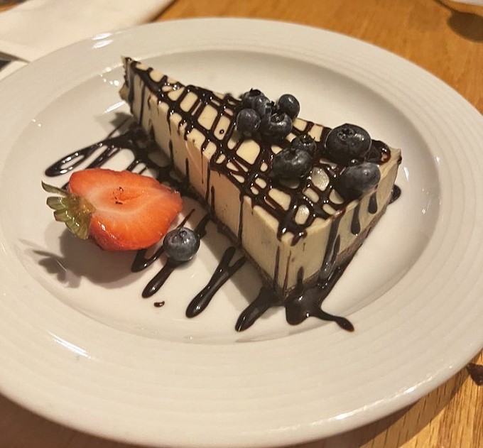 A cheesecake that doesn't just end the meal but crowns it, with chocolate drizzle performing its sacred duty of making everything better.
