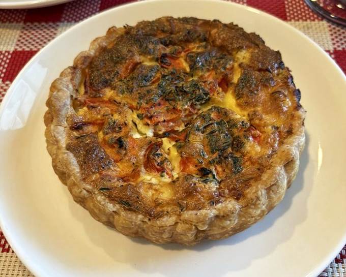 This quiche isn't just baked—it's bronzed to perfection. The crust crimped by hands that understand the architecture of proper French pastry.