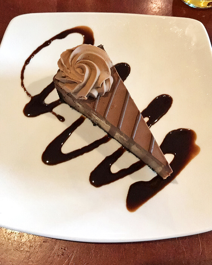 The chocolate cheesecake arrives like the grand finale it deserves to be&mdash;rich, velvety, and adorned with artistic drizzles of sauce that make you pause before diving in.