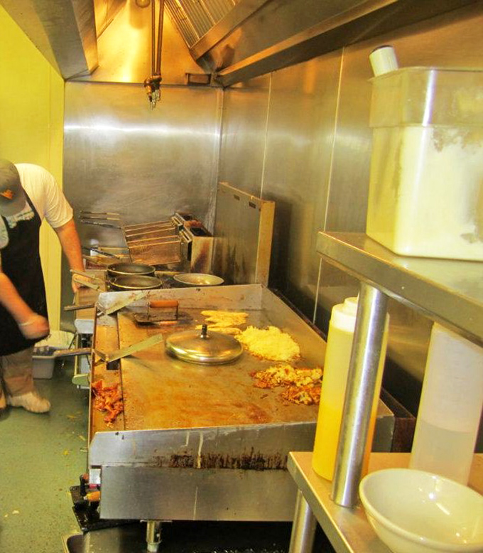 The kitchen battlefield where breakfast dreams become reality. That flat-top grill has probably cooked enough eggs to circle the Earth, if laid end to end.