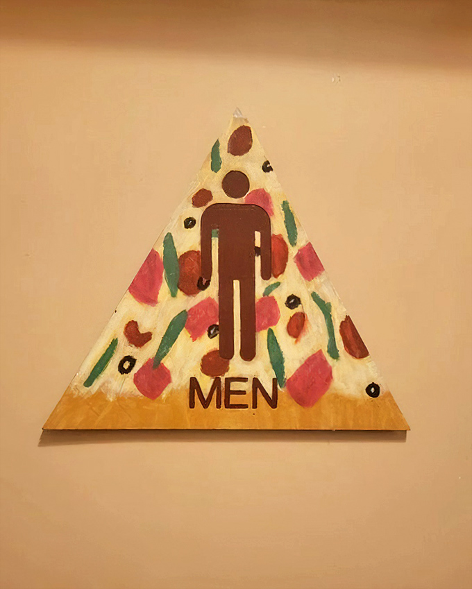 Even the restroom signs have personality. This pizza-shaped men's room marker shows attention to thematic detail extends to every corner of the establishment.