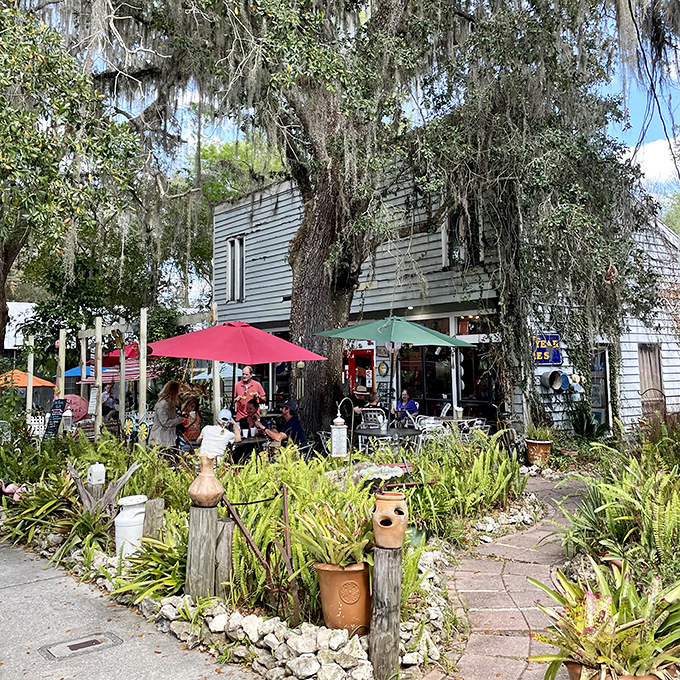Colorful umbrellas and garden whimsy transform dining into an outdoor adventure beneath moss-draped trees.