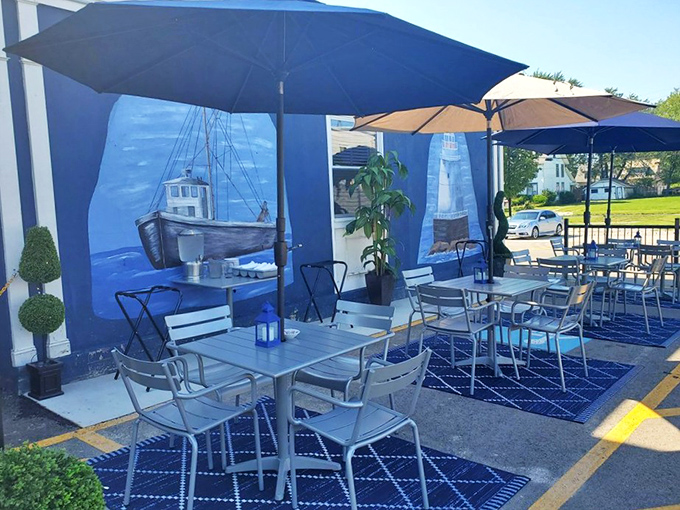 Outdoor dining that captures the lakeside spirit. Blue umbrellas, nautical rugs, and those murals create a maritime escape right in the parking lot.