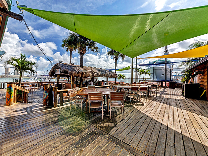 Colorful shade sails flutter overhead like tropical flags, claiming this wooden deck as sovereign seafood territory.