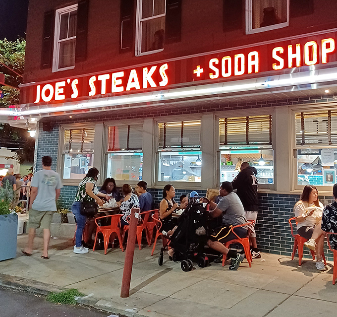 Summer nights at Joe's&mdash;where the neon sign serves as both invitation and nightlight for sidewalk diners seeking cheesesteak salvation.