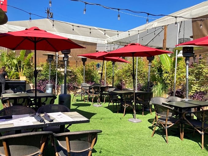 California outdoor dining at its finest &ndash; red umbrellas, lush greenery, and the promise of steak under an open sky.