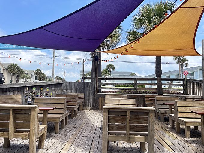 Outdoor seating under colorful shade sails where the sea breeze serves as nature's air conditioning and every table feels like the best seat in the house.