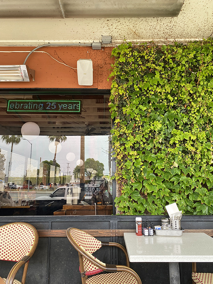 A touch of greenery and outdoor seating with a digital sign celebrating 25 years&mdash;proof that in a city of trends, quality stands the test of time.