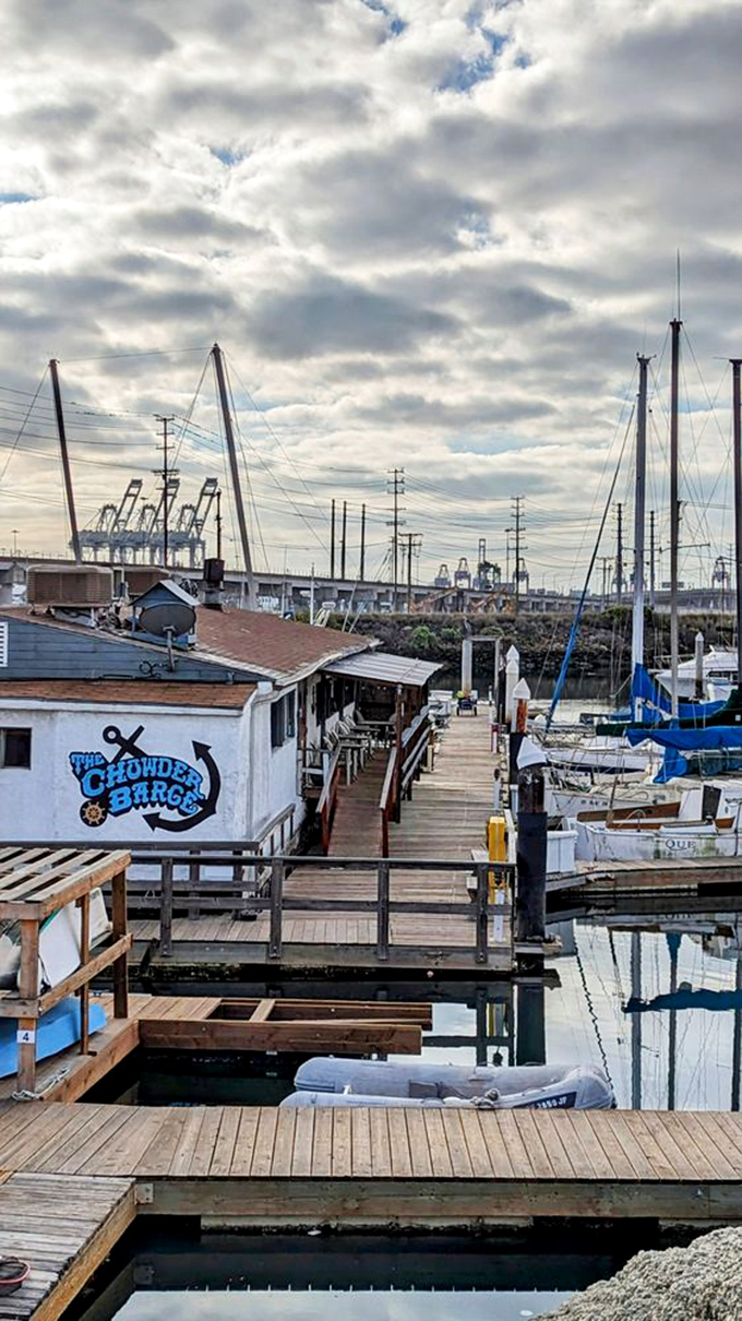 A floating oasis amid industrial giants. The Chowder Barge stands proudly among sailboats with the port's cranes creating a uniquely SoCal backdrop.