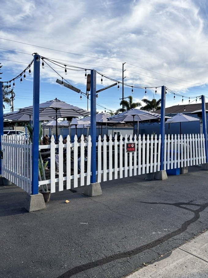The white picket fence and string lights create a coastal charm that says, "Come in, kick off your flip-flops, and stay awhile."