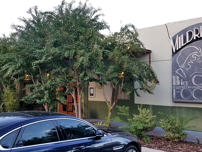 As dusk approaches, Mildred's exterior takes on an inviting glow that seems to whisper, "Yes, you should definitely make a reservation."