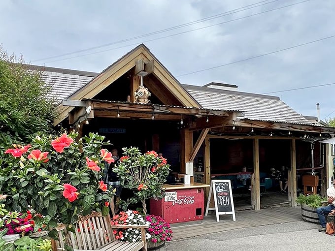 The Cove's flower-flanked entrance promises Michigan hospitality with its weathered wood, vibrant blooms, and the silent promise of whitefish within.