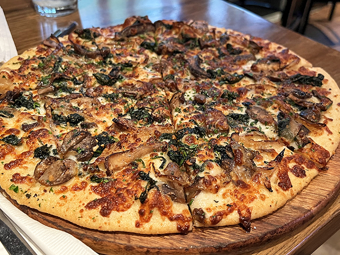 This isn't just pizza&mdash;it's a wooden board of joy topped with mushrooms and greens. The kind of pie that silences conversation with deliciousness.