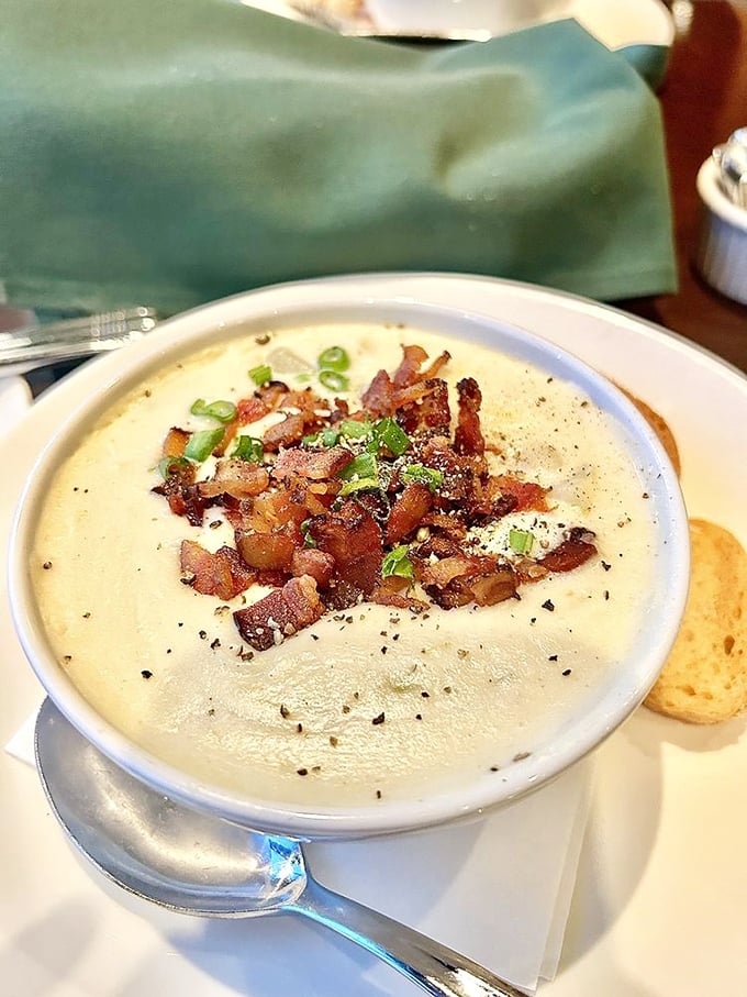 Velvety potato soup crowned with crispy bacon bits and green onions &ndash; proof that simple ingredients become extraordinary in the right hands.