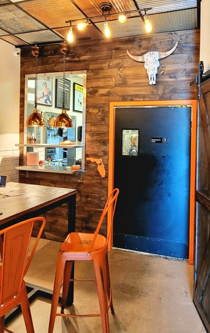 Orange chairs pop against wooden walls adorned with a decorative skull. That pendant lighting casts the perfect glow for serious meat appreciation.