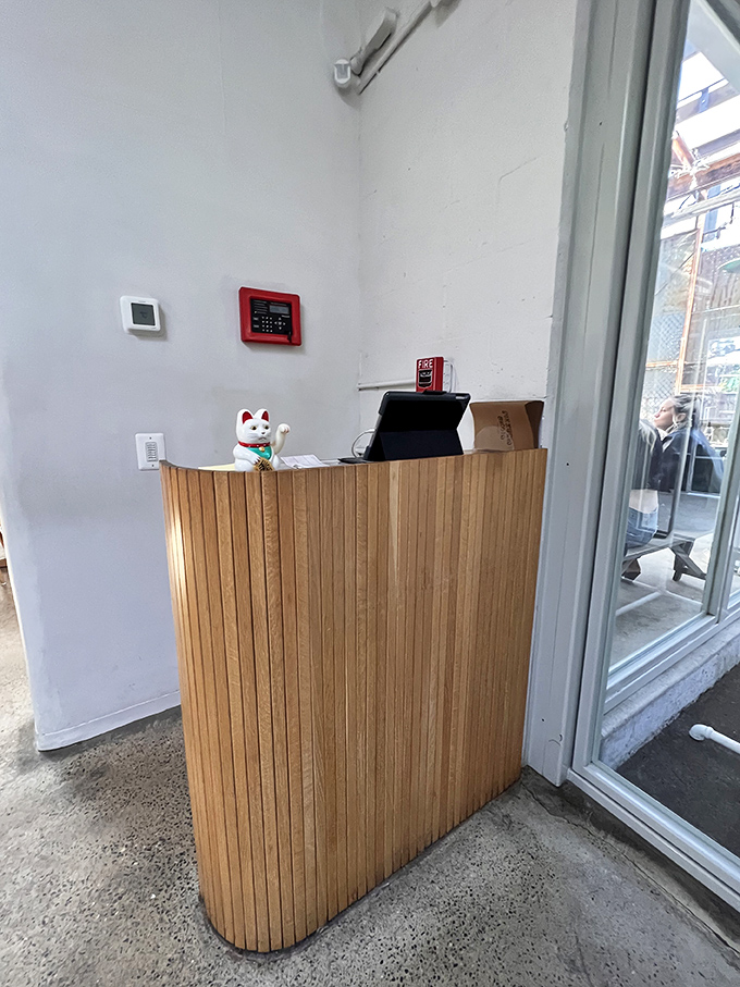 The reception desk's wooden slats and lucky cat welcome you to an experience that's both meticulously designed and warmly inviting.