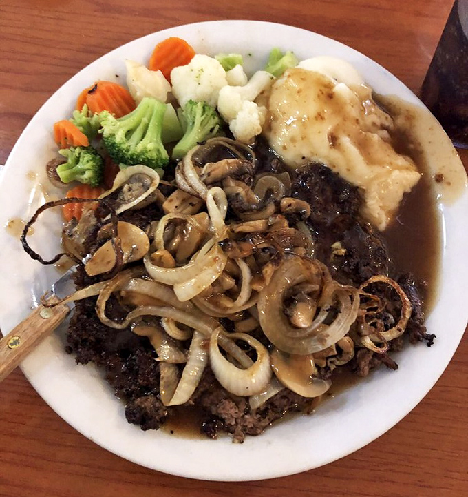 Salisbury steak smothered in mushrooms and onions with a side of colorful veggies—comfort food that your grandmother would approve of.