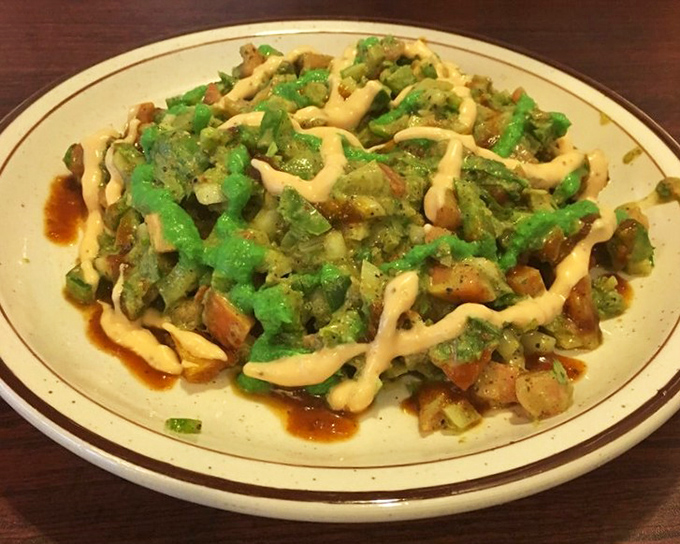 Samosa chaat that's having an identity crisis in the best possible way—part appetizer, part main event, all delicious with that zigzag of creamy sauce.