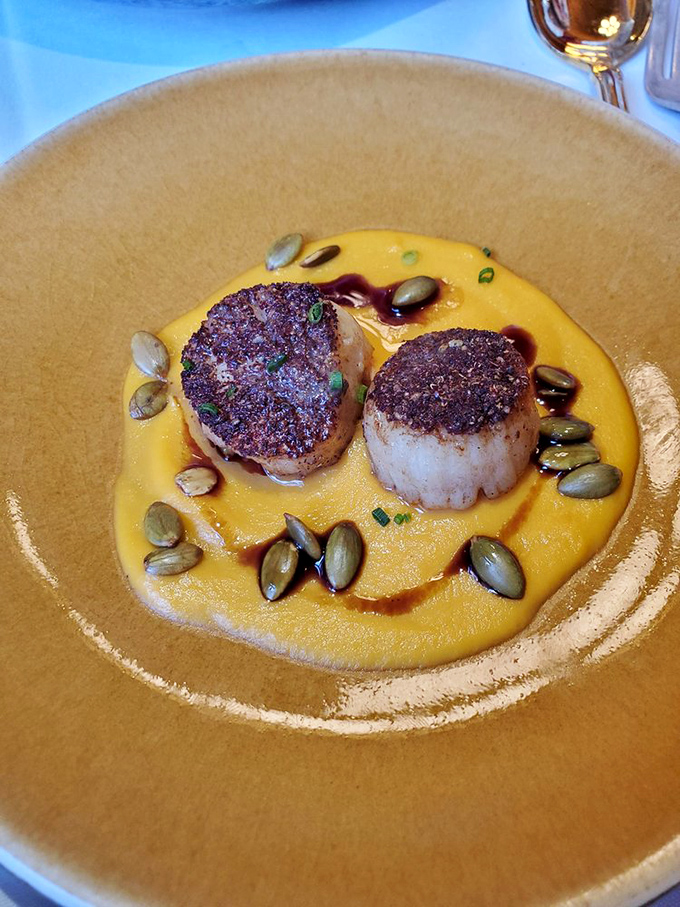 Scallops seared to golden perfection, nestled on a sunset-colored puree. Those pumpkin seeds aren't just garnish&mdash;they're the perfect crunchy counterpoint to the buttery shellfish.