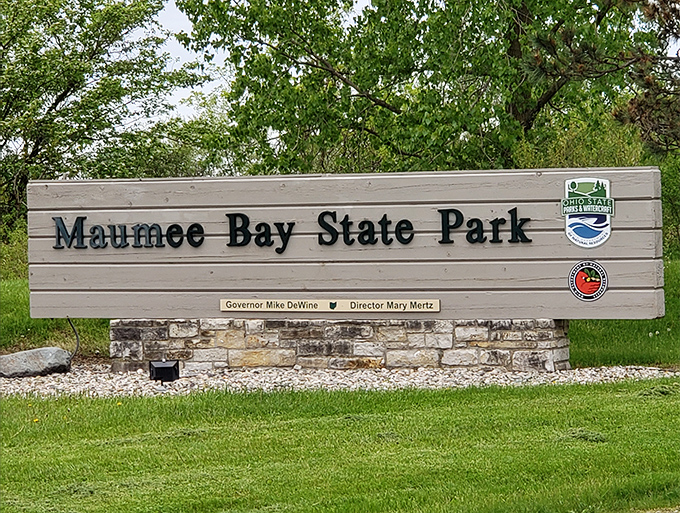 The welcoming sign to Maumee Bay State Park, where adventures begin and stress dissolves faster than an aspirin in hot coffee.