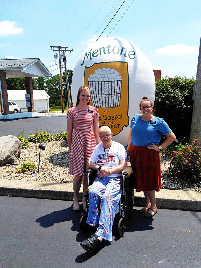 Three generations pose with Mentone's famous landmark, proving the egg's appeal spans from grandparents to grandchildren.