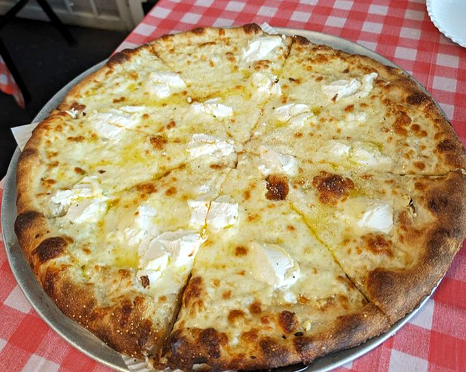 The white pizza showcases ricotta's creamy magic &ndash; like clouds of dairy goodness that make you forget tomato sauce ever existed. 