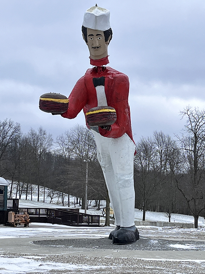 Winter transforms the bobblehead into a seasonal attraction, his red jacket popping dramatically against the snow-covered landscape.