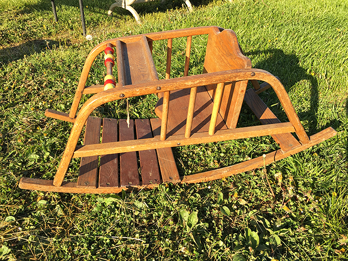 A vintage wooden rocking sled waits patiently in the grass. Some lucky child will soon experience the same joy it brought generations ago.
