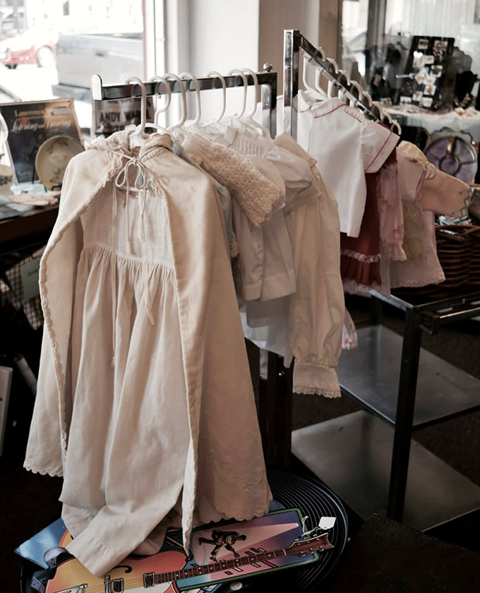Delicate vintage children's clothing hangs like tiny ghosts of fashion past, each piece more charming than anything you'd find in today's department stores.