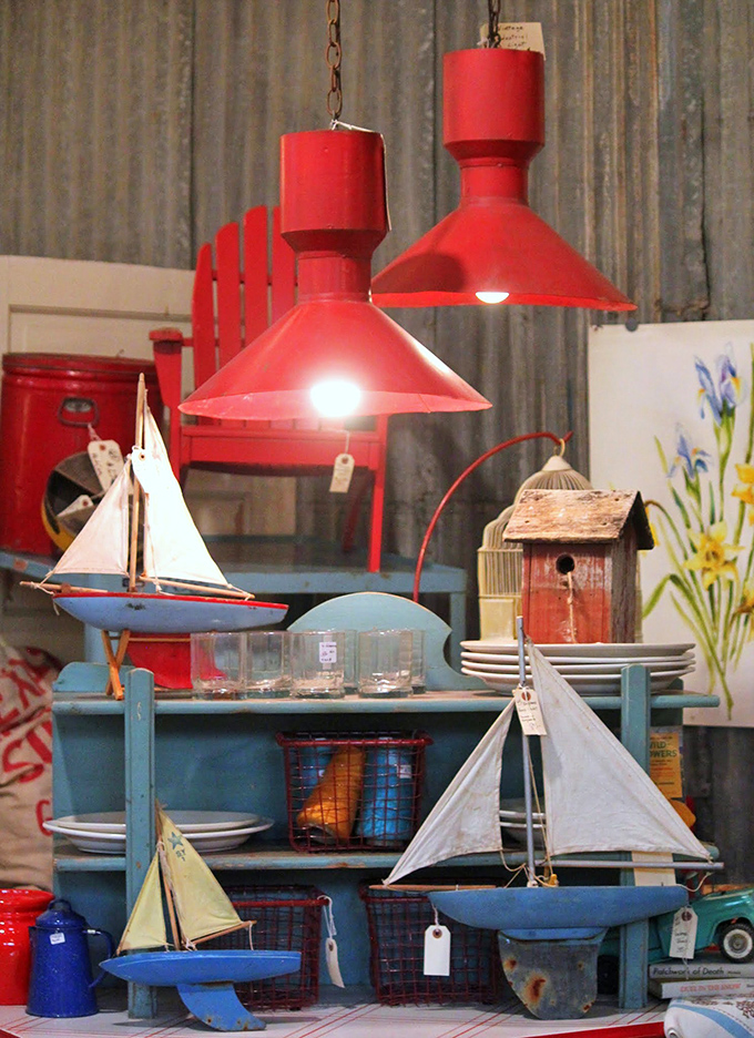 Nautical nostalgia floats through this coastal-themed corner, where model sailboats and bold red pendant lights create an unexpected maritime escape in the desert.
