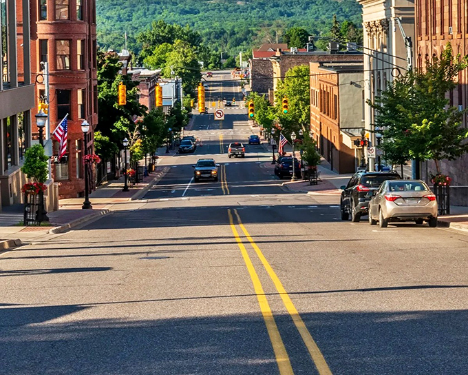 Downtown Marquette's tree-lined streets lead toward distant hills, creating a perfect postcard of urban charm nestled within the Upper Peninsula's natural beauty.