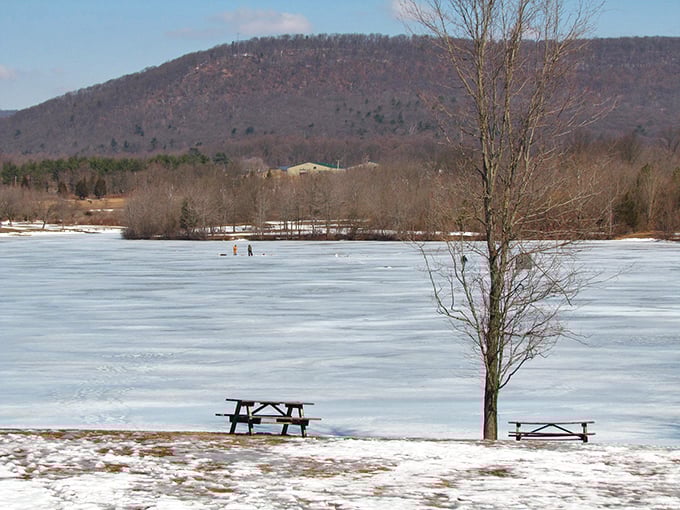 Winter transforms Memorial Lake into a frozen playground where brave souls venture onto the ice while the mountains stand watch in the distance.