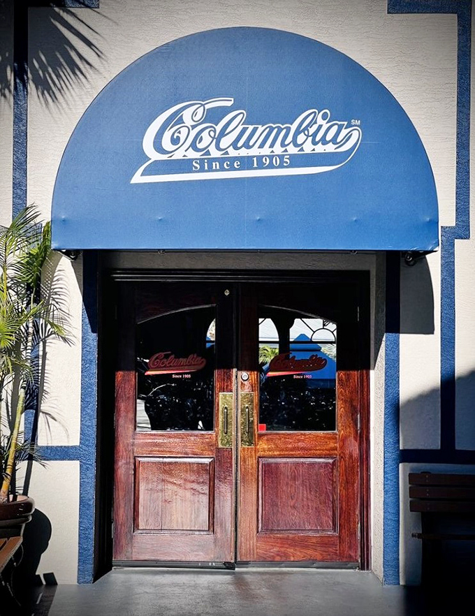 Those blue awnings and wooden doors aren't just an entrance; they're a portal to a century-old Florida institution where time slows down and appetites perk up.