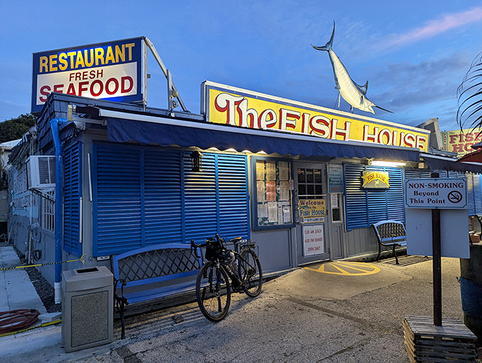 As dusk falls, The Fish House's neon sign becomes a beacon for hungry travelers. That marlin silhouette knows what you need.