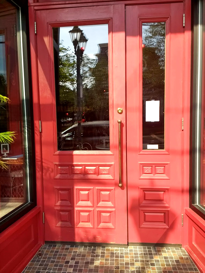 The red doors stand like guardians of joy, their vintage panels and brass hardware promising sweet adventures within.