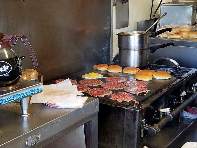 Patties sizzle alongside toasting buns on a well-seasoned flat top - the altar where ordinary ingredients become extraordinary meals.