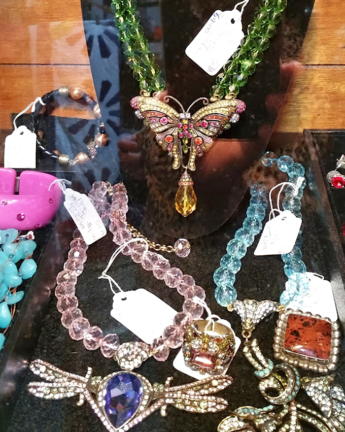 Butterfly pendants and gemstone jewelry sparkle under glass, waiting for their next chapter. Yesterday's special occasion accessories become tomorrow's vintage treasures.