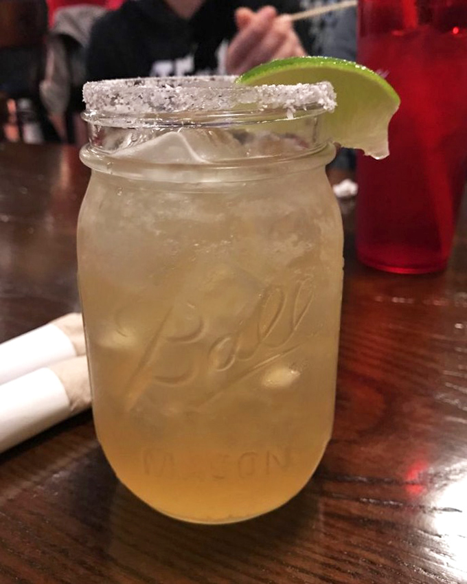 A mason jar margarita with a salt-rimmed crown and lime accent. This isn't just a drink—it's liquid sunshine with a refreshing kick.