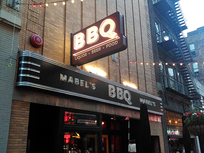 As evening falls, Mabel's neon sign glows like a beacon for the hungry. It's not just illumination&mdash;it's a promise of smoky delights.