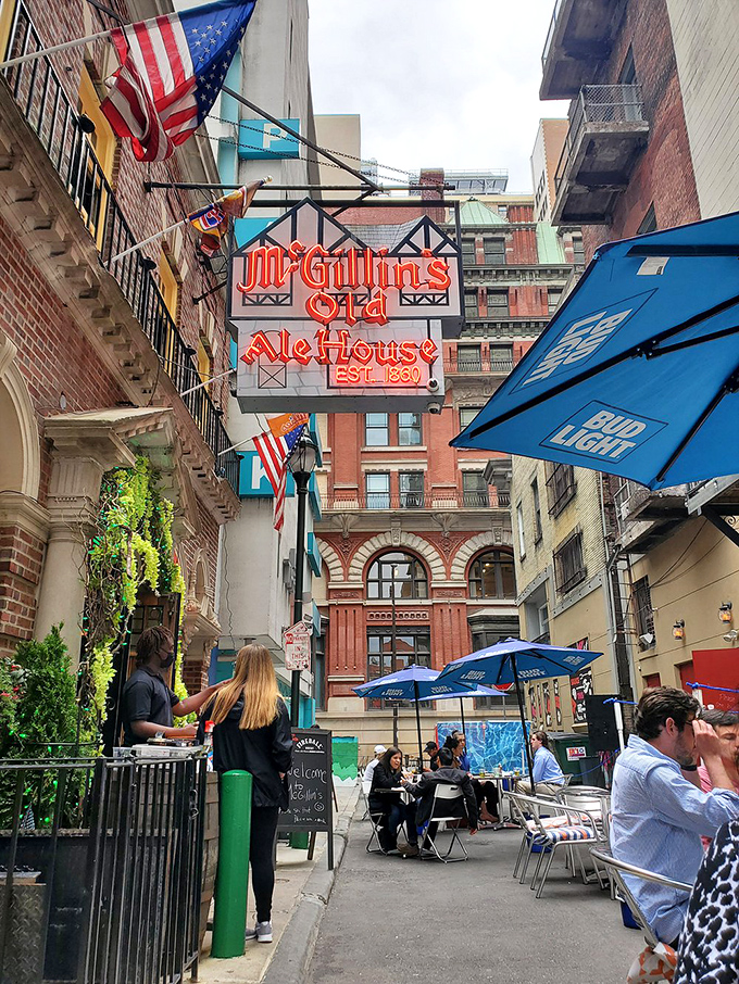 McGillin's alley seating offers urban dining with a side of people-watching—Philadelphia life unfolding beneath the watchful gaze of that iconic sign.