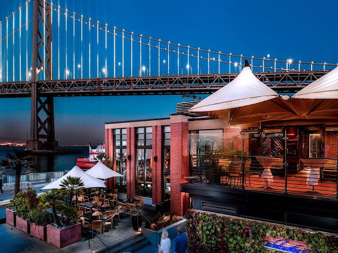 Dusk transforms the outdoor space into a postcard-perfect scene where palm trees and the illuminated bridge create California magic you can't bottle.