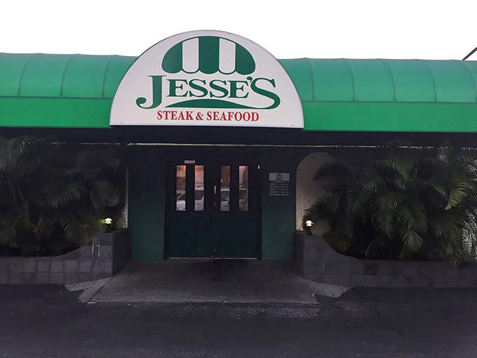 As evening falls, Jesse's transforms into a green-awninged oasis of culinary comfort. The entrance promises satisfaction beyond those doors.