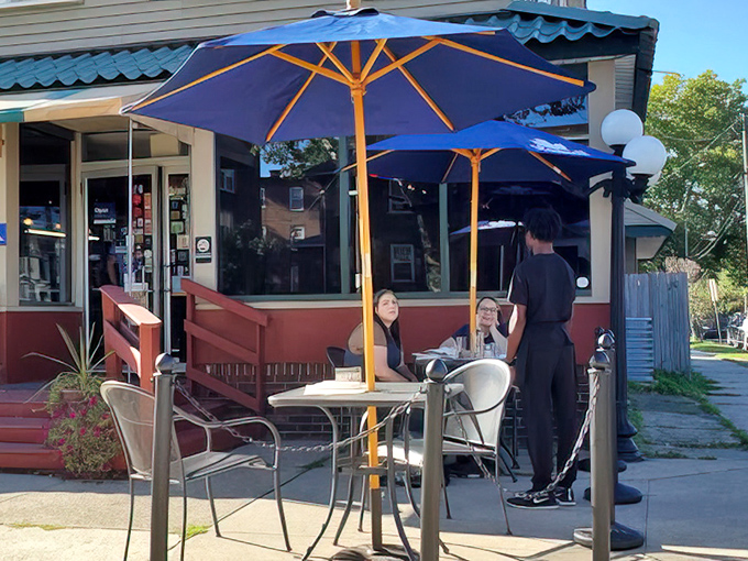 Outdoor seating under bright blue umbrellas offers a perfect perch for people-watching while savoring Southern specialties on sunny Erie days.
