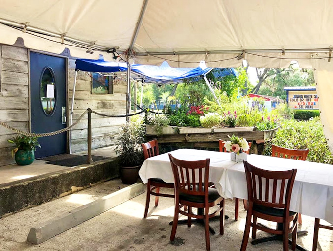 Outdoor dining under a canvas canopy, where fresh air seasons every bite. Florida's natural beauty becomes part of the meal.