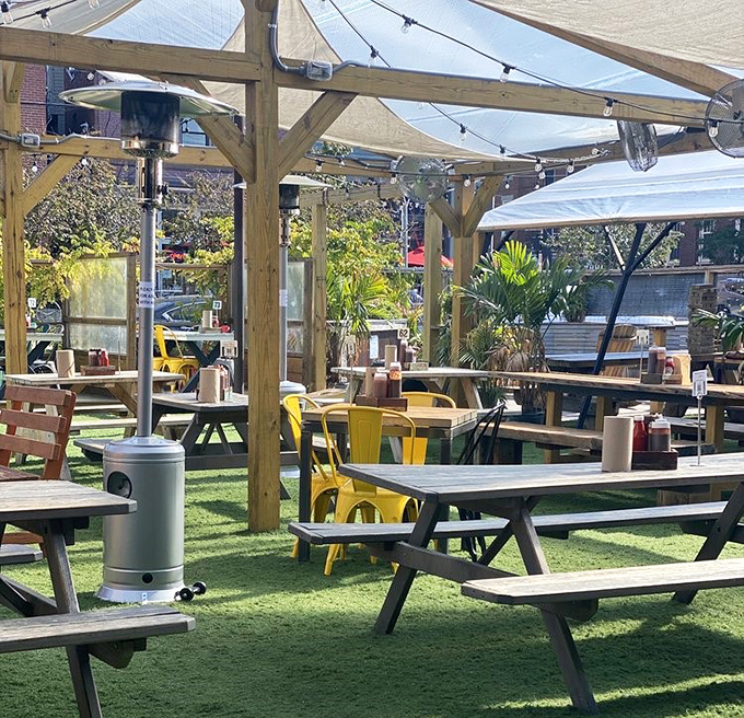 Picnic tables under wooden pergolas create the perfect outdoor BBQ oasis. Yellow chairs add pops of sunshine even on cloudy days.