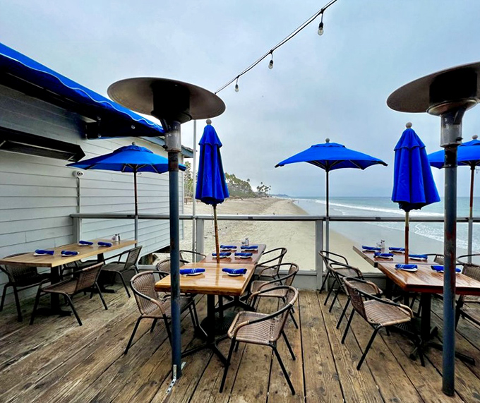 Outdoor dining that makes indoor tables seem like punishment. These blue umbrellas and ocean views elevate every bite to memorable status.
