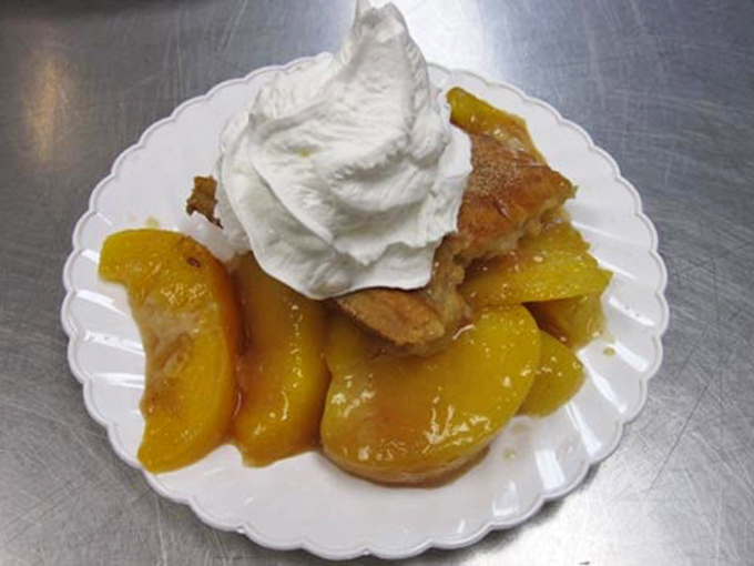 Peach cobbler topped with a cloud of whipped cream. Because after conquering mountains of smoked meat, your sweet tooth deserves its moment of glory too.