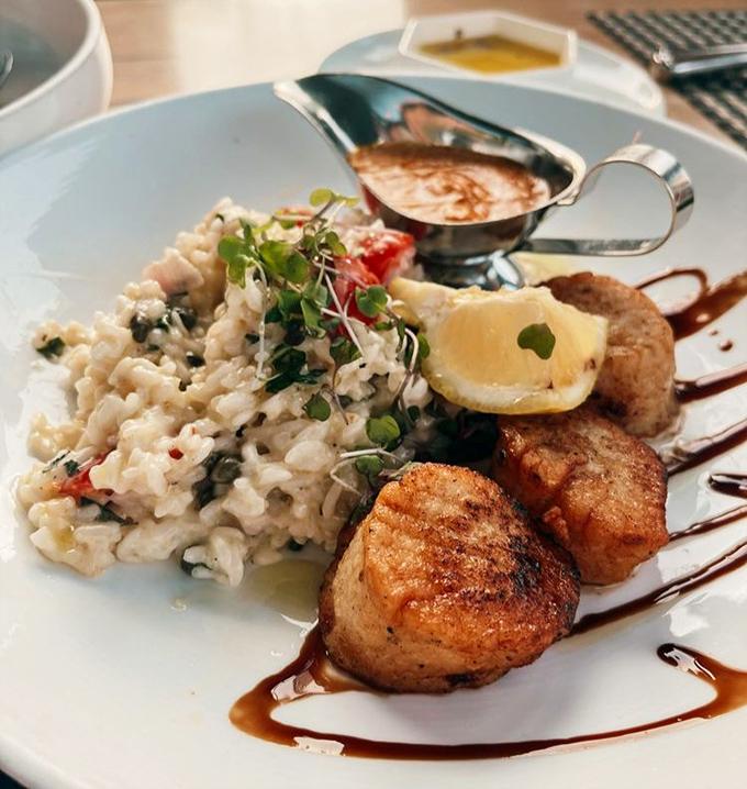 Perfectly seared scallops nestle against creamy risotto like old friends catching up, while the sauce boat stands ready to elevate the reunion to legendary status.