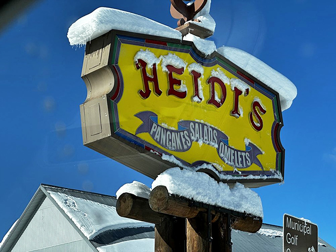 The snow-dusted sign stands as a beacon for breakfast pilgrims, promising pancakes, omelets, and salvation from hotel buffet mediocrity.