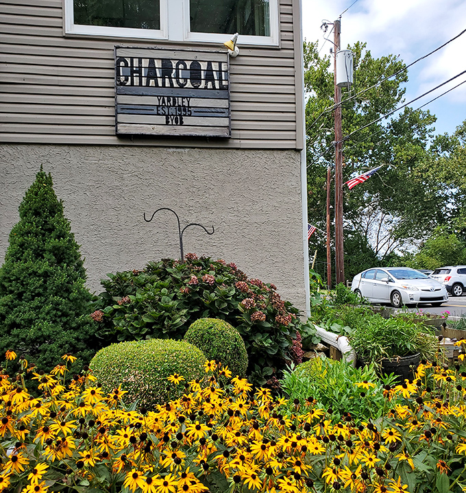 Summer blooms frame the Charcoal sign like nature's own marketing department, creating a first impression that promises seasonal freshness inside.